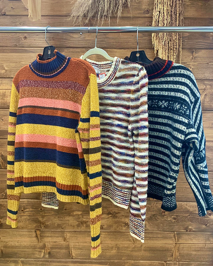 Cozy knits in a rainbow of patterns hang ready for their next adventure—that striped sweater is practically screaming "autumn road trip!"