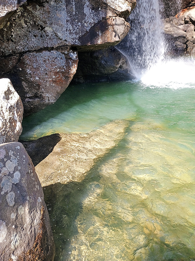 The emerald pool beneath the falls invites contemplation, its clarity revealing secrets of the riverbed like nature's own display case.