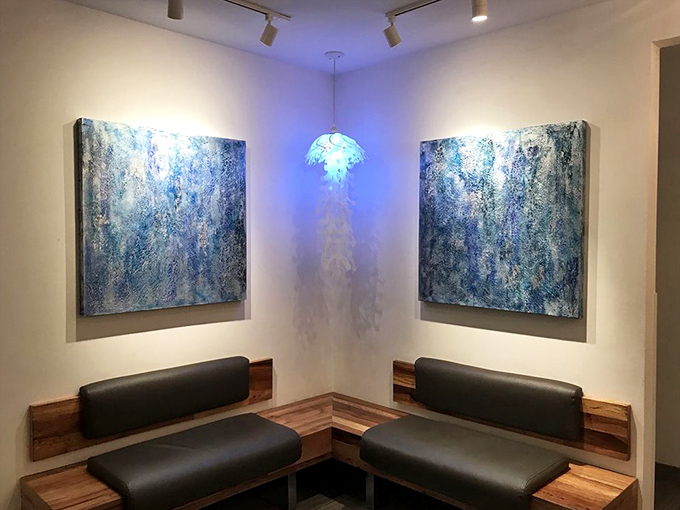Blue artwork and a jellyfish-inspired light fixture create a serene corner that feels like dining inside an ocean-themed dream.