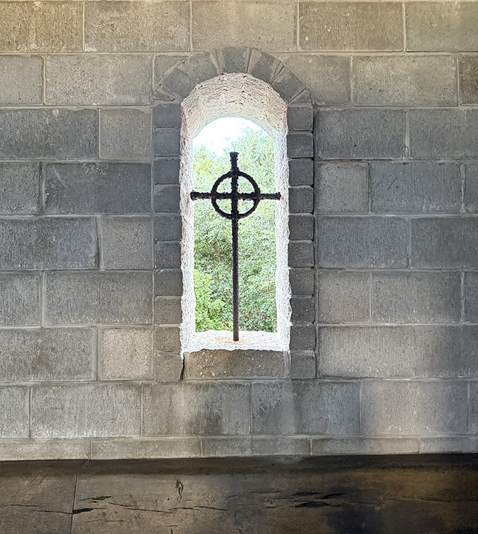 A simple cross-shaped window frames the lush Florida landscape, merging medieval symbolism with tropical surroundings.