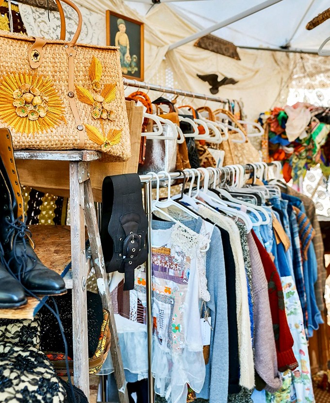 A straw purse with sunflower details hangs among vintage clothing racks&mdash;summer fashion that hasn't changed much since your mother wore it to Woodstock.