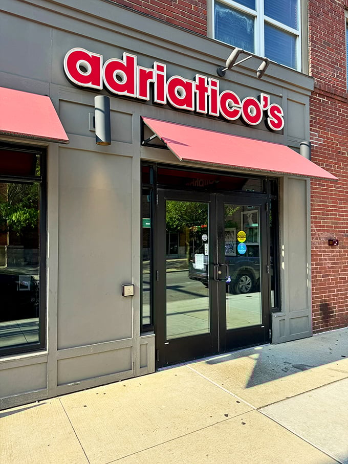 Sunshine highlights Adriatico's welcoming entrance, where pizza perfection awaits behind those gleaming glass doors.
