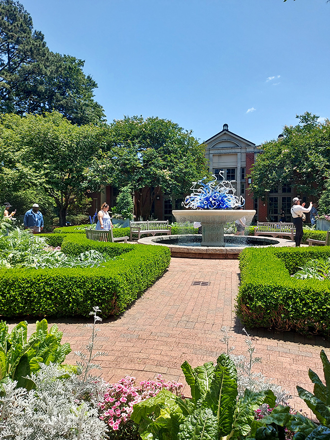 The formal garden's geometric precision creates nature's perfect living room, complete with a bubbling water centerpiece.