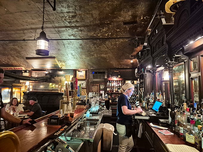 The bar gleams with bottles and polished wood, while the weathered ceiling above tells stories of centuries of toasts, celebrations, and commiserations.