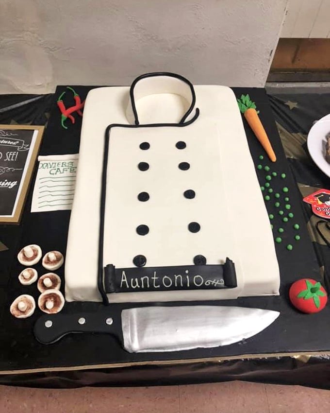 A chef's coat cake that's more realistic than some actual uniforms I've owned. The fondant knife and vegetables show serious attention to detail.