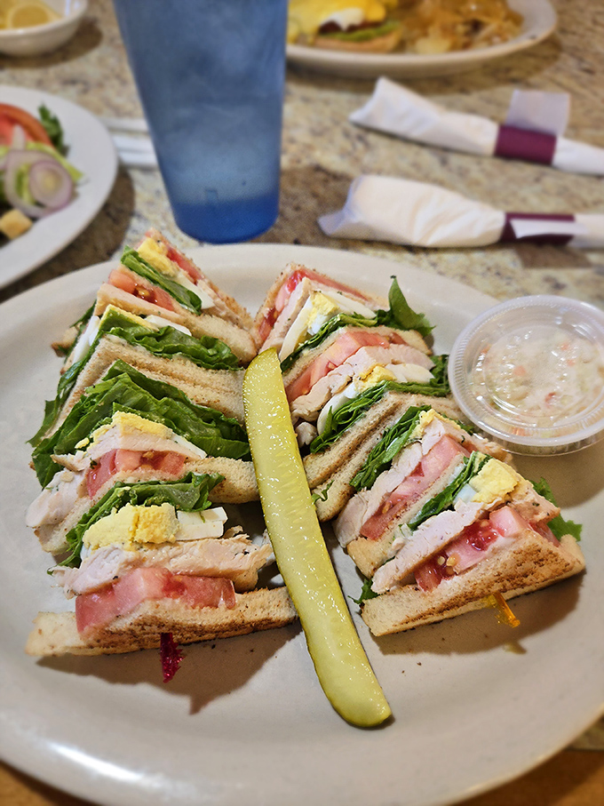 The club sandwich &ndash; architectural marvel of the diner world, where each perfectly stacked layer tells its own delicious story. That pickle means business!