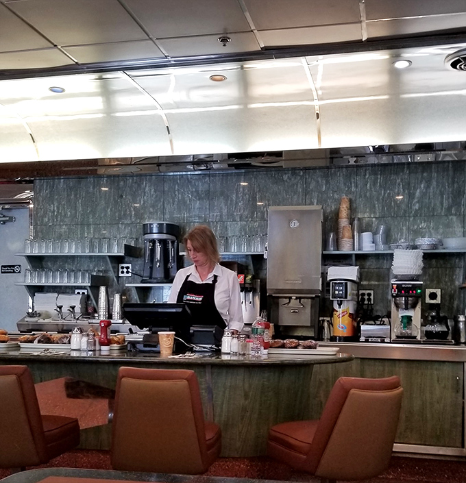 Behind the counter, where coffee flows like conversation and the rhythmic dance of short-order cooking has been perfected over decades of practice.