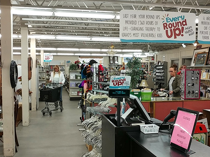 The bustling checkout area where treasure hunters complete their quests, beneath banners reminding shoppers their purchases fund therapy for Idaho's kids.