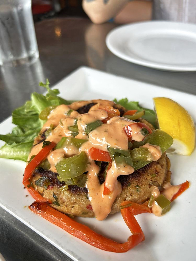 This crab cake wears its pepper and sauce toppings like a fashionable hat at the Kentucky Derby of seafood.