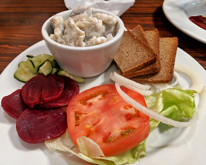 A traditional Danish plate featuring creamed herring, dark rye bread, and fresh vegetables—a taste of Nordic simplicity that's been perfected over centuries.