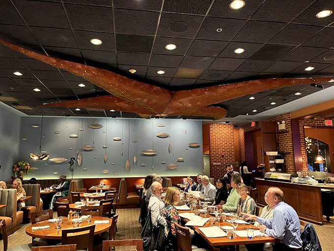 Happy diners gather beneath the dramatic octopus ceiling installation, proving great seafood brings people together better than any social media platform.