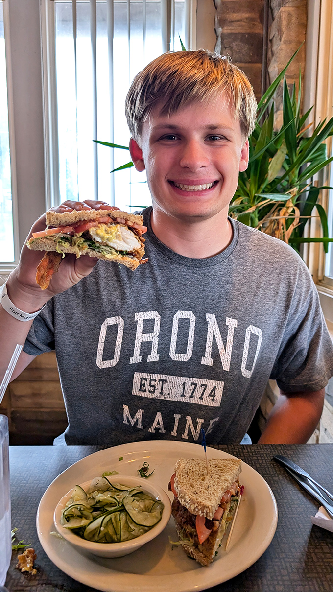 A smiling diner proudly displays his sandwich conquest – the universal expression of "you've got to try this!"