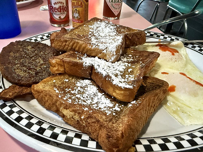 French toast stacked higher than your weekend plans, dusted with powdered sugar like freshly fallen snow. Breakfast architecture at its most delicious.