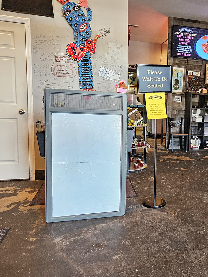 The welcoming entrance with colorful artwork and "Please Wait To Be Seated" sign greets hungry guests at this beloved spot.