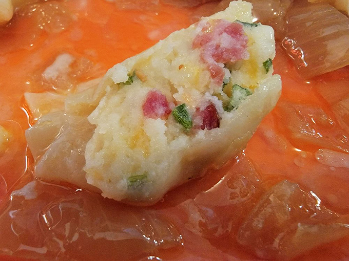 A pierogi taking a bath in what might be the world's most flavorful soup. The bits of ham and vegetables are like little flavor confetti.