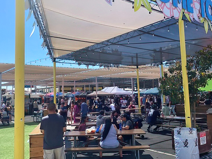 The social heart of the market where strangers become friends. This dining area transforms food court culture into community gathering under California sunshine.