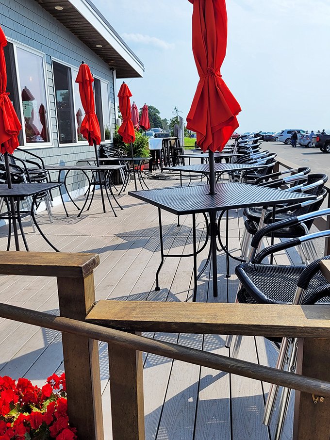The outdoor patio, with its cheerful red umbrellas, offers al fresco dining where the sea breeze serves as both ambiance and appetizer.