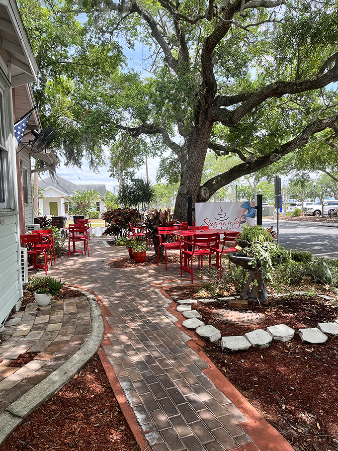 A brick pathway leads to paradise under sprawling oak trees. These red tables have witnessed countless first dates and life-changing conversations.