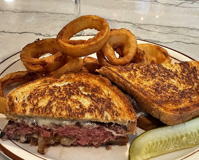 This patty melt isn't just a sandwich&mdash;it's an engineering marvel of beef, cheese, and grilled onions. Those onion rings are the perfect sidekick.