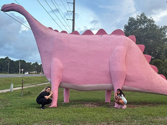 Finding creative ways to pose with a pink dinosaur becomes an art form. These visitors have clearly mastered the technique!