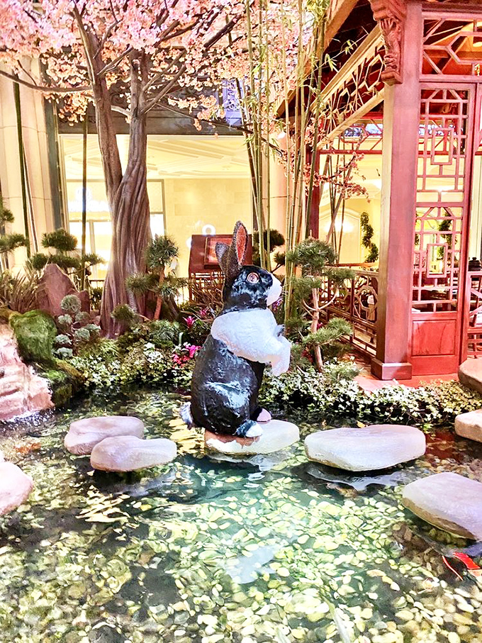 This contemplative rabbit seems to be pondering life's big questions while visitors snap photos of his serene water garden.