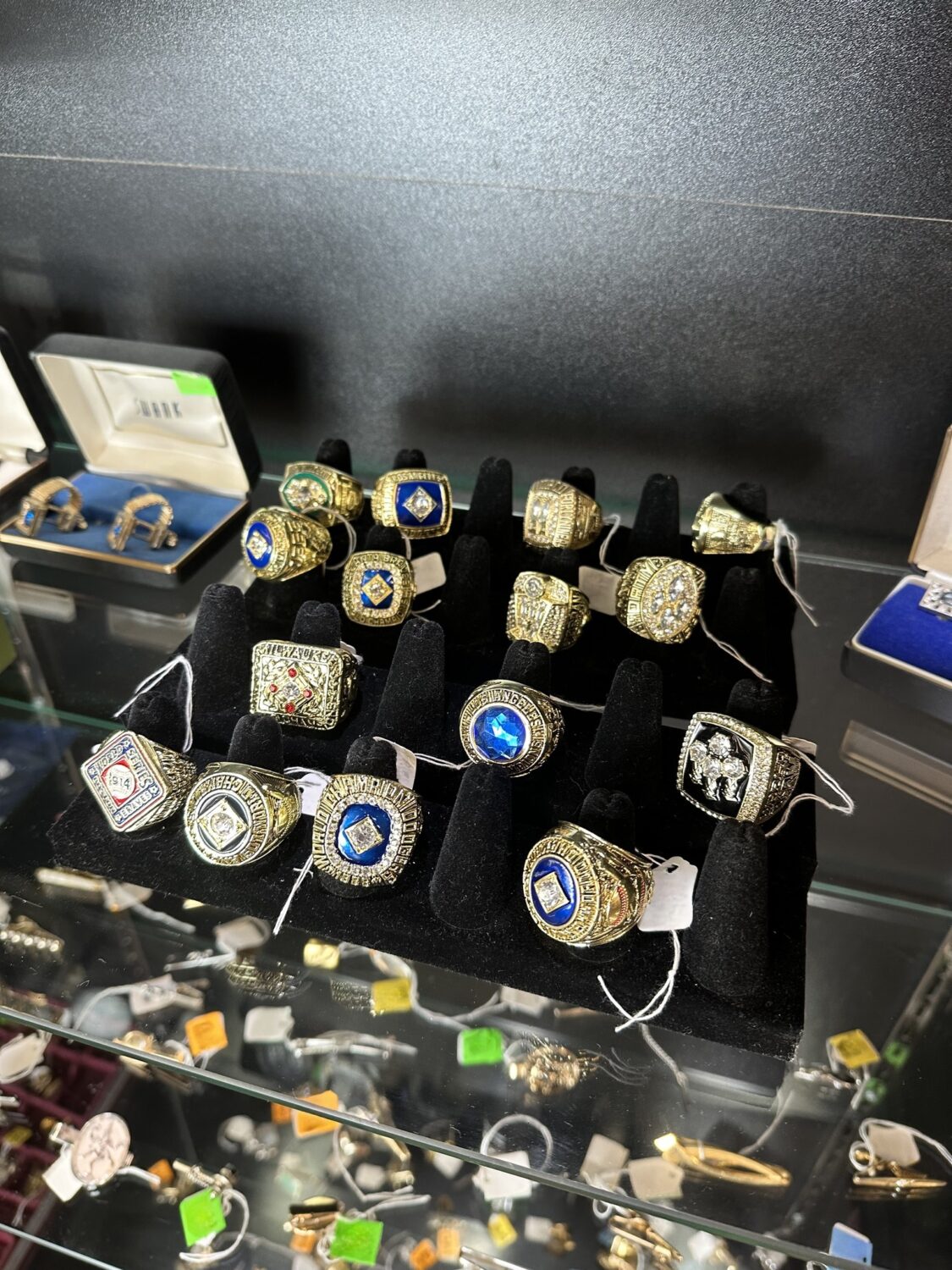 Shiny championship rings displayed in this glass case invite you to admire their golden glow and celebrate legendary sporting victories.