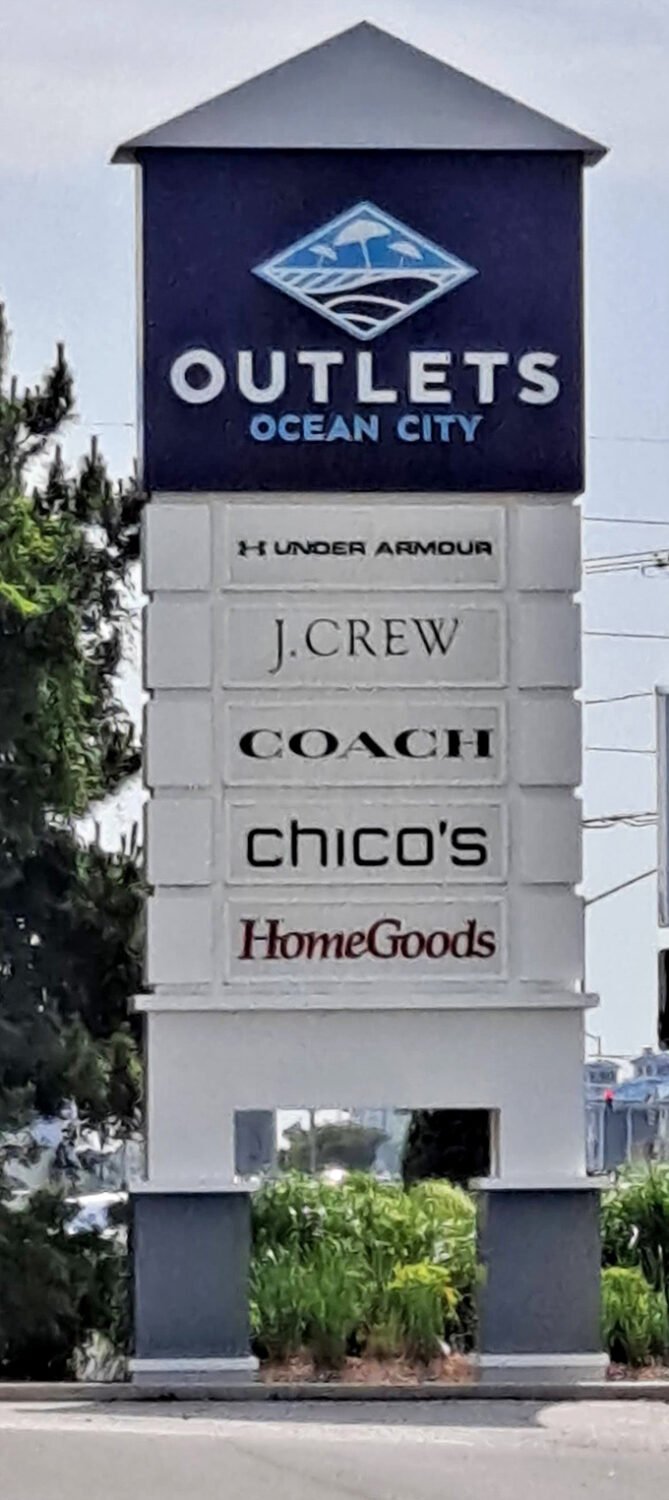 The outlet mall marquee stands tall, a beacon of hope for credit cards yearning to be swiped and shoppers seeking retail therapy.