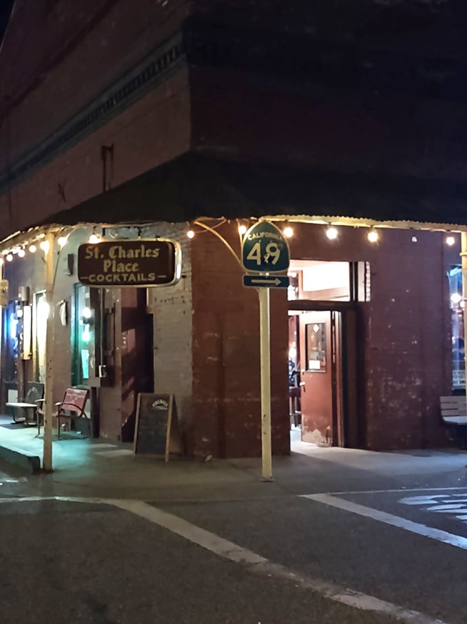 Night transforms St. Charles Place into a beacon for thirsty travelers, where string lights and Highway 49 signs guide you to local libations.