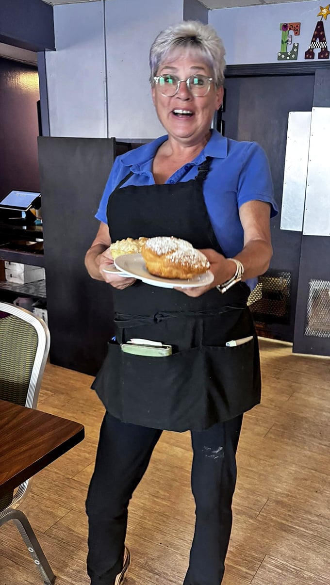 A staff member proudly displays a pastry creation with the joy of someone sharing their grandmother's secret recipe.