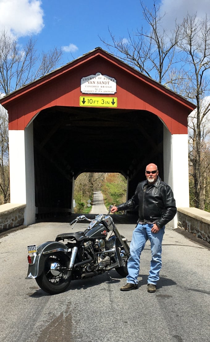A motorcycle enthusiast and his vintage ride create a perfect pairing with the historic bridge&mdash;two classics from different eras meeting.
