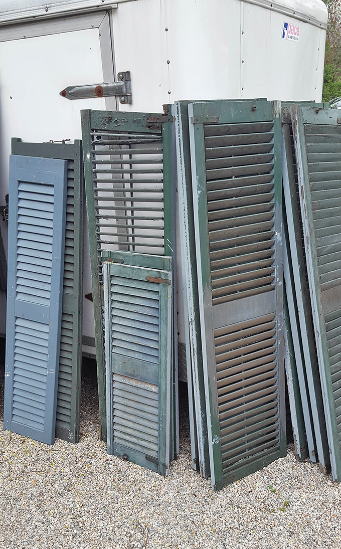 Weathered shutters lean against each other like old friends sharing secrets about the windows they once protected.