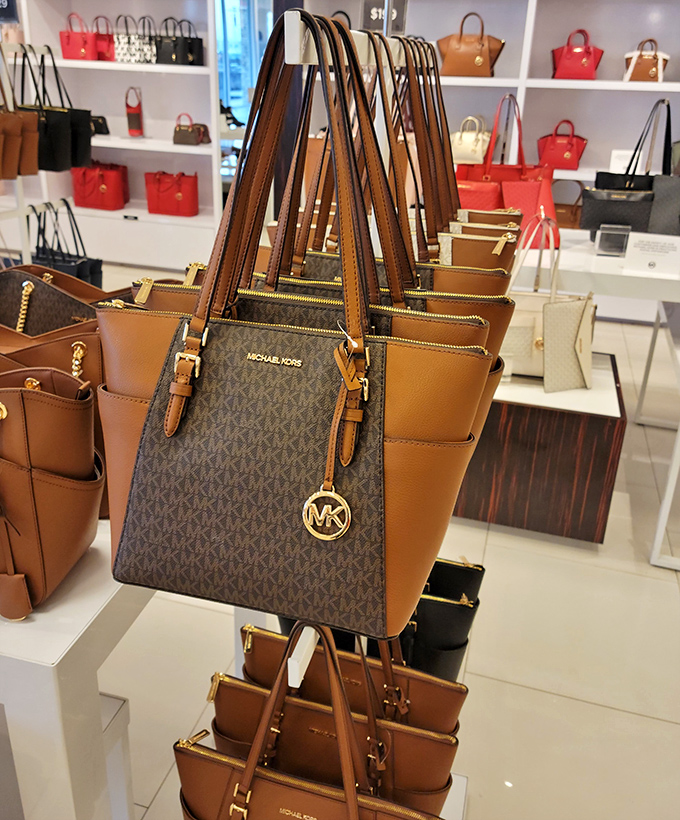 Michael Kors handbags standing at attention, ready to transform shopping carts into fashion statements without requiring a second mortgage.