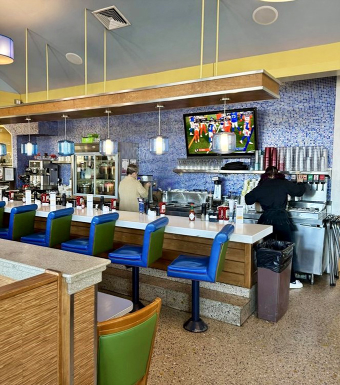 The counter seating – where solo diners become temporary family and the coffee is always flowing. Blue and green chairs add that coastal pop.