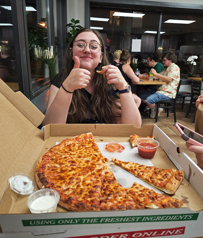 The universal thumbs-up &ndash; when words fail, gestures speak volumes about the pizza that's disappearing faster than you can say "Pittsburgh perfection."