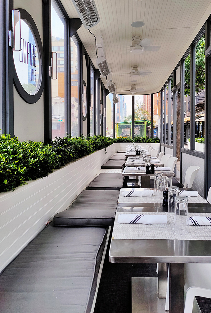 Sunlight streams through windows onto pristine white tables, creating a dining space where Mad Men characters would feel right at home discussing their latest accounts.