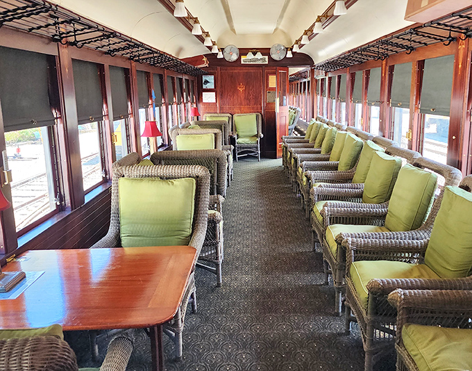 Wicker chairs with plush green cushions line this observation car. Imagine sipping a cocktail here while the countryside rolled by your window like a living painting.