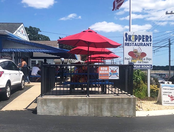 The outdoor dining area offers a front-row seat to Connecticut coastal life, with red umbrellas providing shade for serious seafood business.