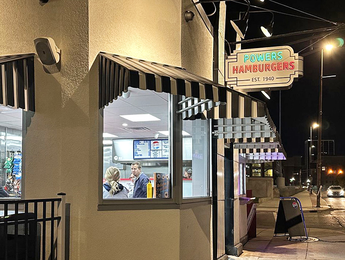 As night falls, the illuminated Powers sign serves as a beacon for hungry travelers and locals alike, promising satisfaction just steps away.