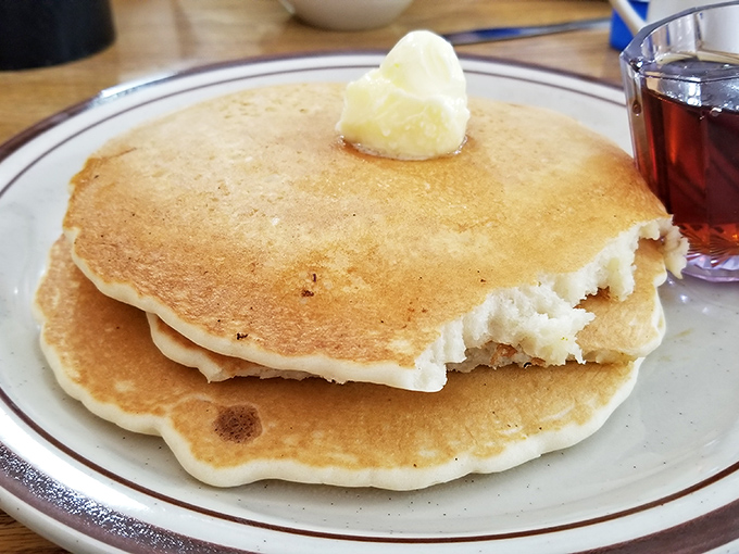Golden-brown pancakes with that perfect butter pat slowly melting into a warm, fluffy landscape. Breakfast poetry on a plate.