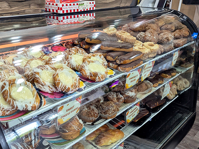 The pastry case—a glass-enclosed museum of carbohydrate artistry where willpower goes to die and "I'll just have one bite" becomes a laughable concept.
