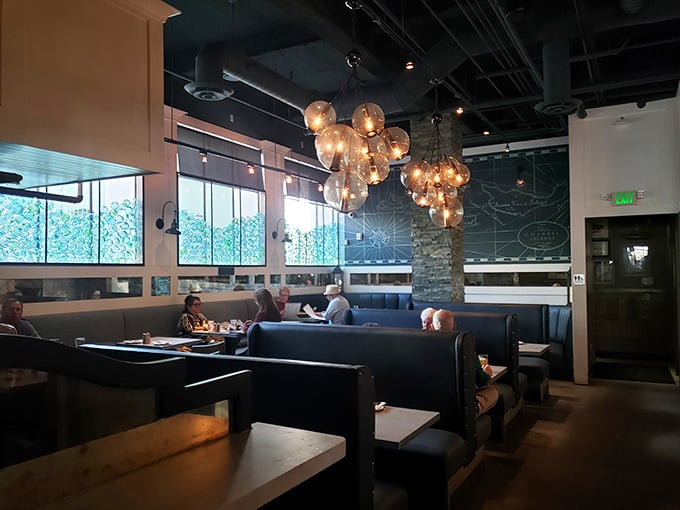 Cozy booth seating illuminated by clusters of glass globe lights creates intimate dining spaces. The nautical map on the wall reminds you of exactly why you're here: for treasures from the sea.