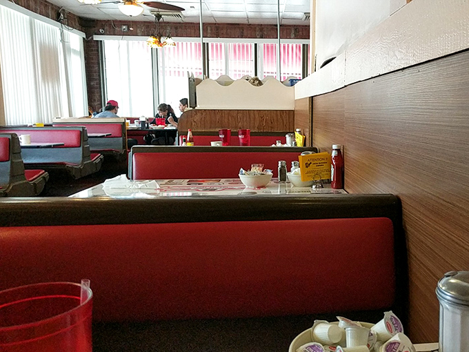 Red vinyl booths cradle conversations between old friends and new acquaintances, while condiment caddies stand ready for any flavor emergency.