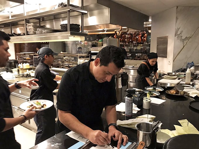 The kitchen team works with focused precision, turning pristine ingredients into edible masterpieces with the concentration of symphony conductors.