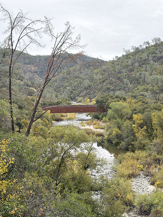 Even on cloudy days, the bridge stands as a warm, russet landmark against the muted greens and grays of the landscape.