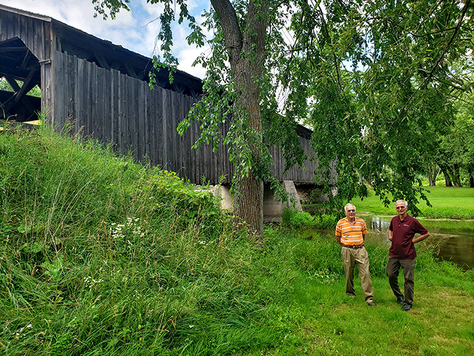 Visitors stroll alongside the historic structure, perhaps contemplating how many footsteps have crossed this creek over the centuries.