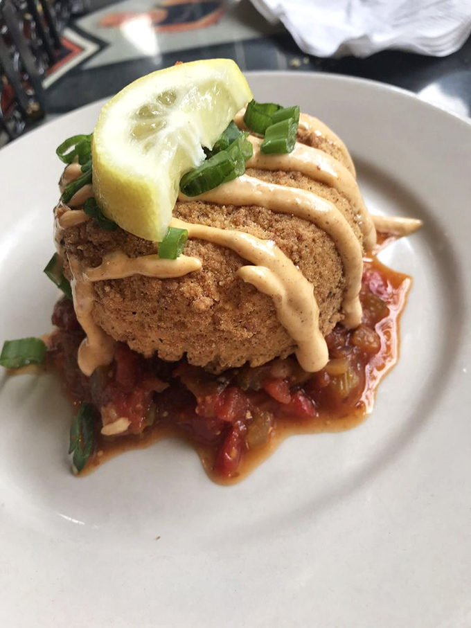 This crab cake isn't just sitting on the plate &ndash; it's posing, showing off its golden crust and saucy personality with lemon-wedge flair.