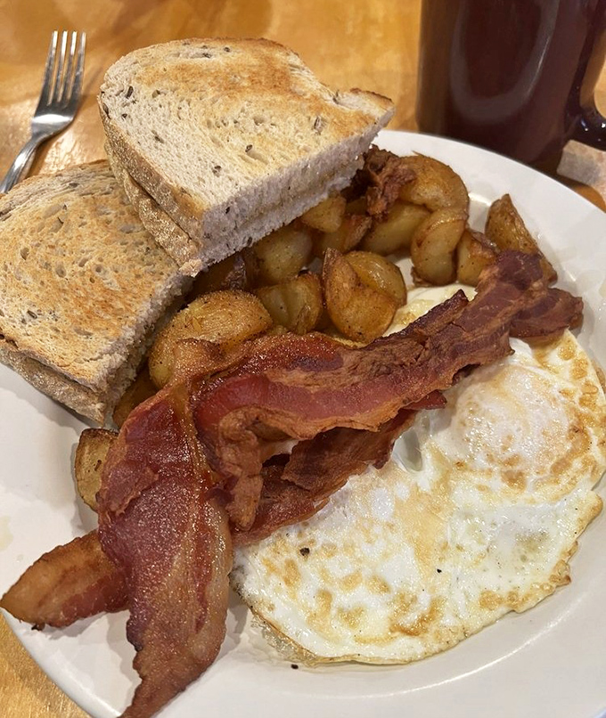 The breakfast trinity: perfectly cooked eggs, crispy bacon, and potatoes that somehow manage to be both crisp and tender. Morning salvation on a plate.