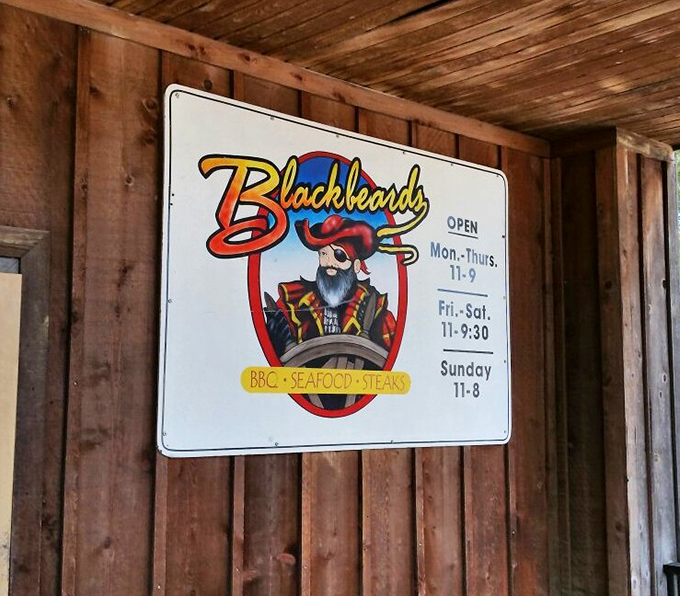 The pirate himself stands guard at the entrance, promising treasures of BBQ, seafood, and steaks – the kind of sign that makes you cancel your other dinner plans.