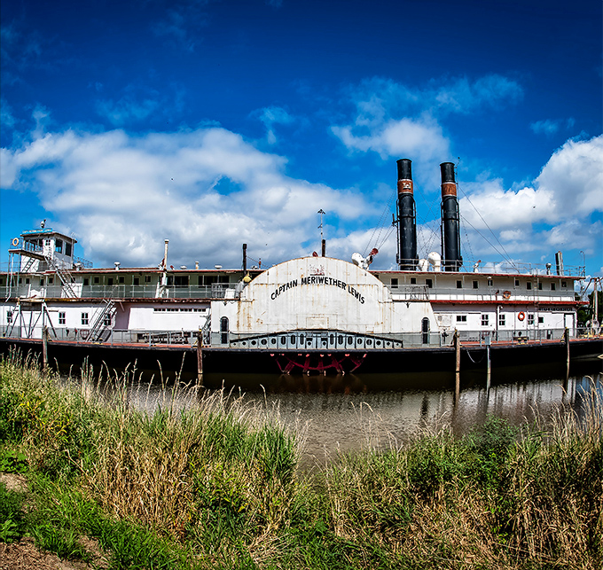 The Captain Meriwether Lewis Dredge rests majestically along the Missouri's banks, a retired river workhorse now telling tales of the mighty waterway.