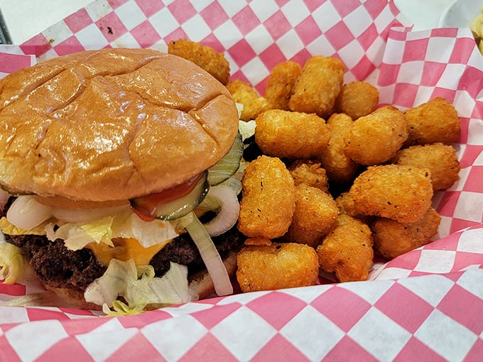 This isn't just a burger&mdash;it's a proper American classic, nestled beside golden tater tots on a red-checkered backdrop of nostalgia.